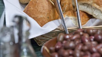 Uma cesta com pães e azeitonas sobre uma mesa.