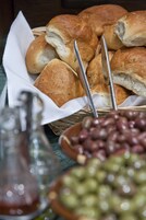 Uma cesta com pães e azeitonas sobre uma mesa.