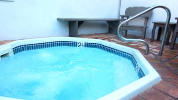 Piscina com escada de metal, um banco e uma placa na parede.