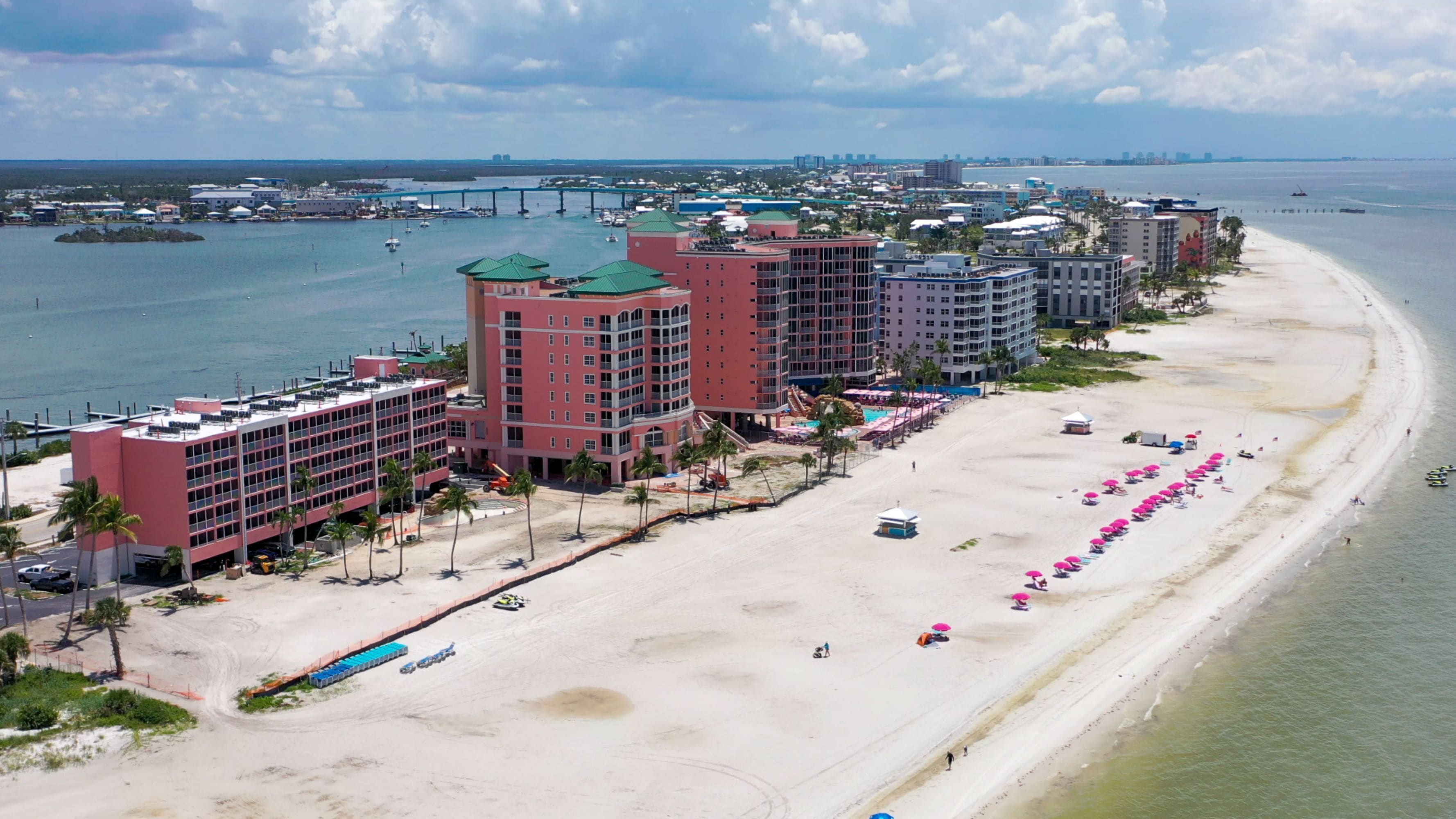 Um hotel à beira-mar com vários edifícios, uma praia arenosa e vista para o oceano e o horizonte da cidade.