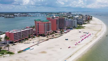 Um hotel à beira-mar com vários edifícios, uma praia arenosa e vista para o oceano e o horizonte da cidade.