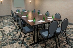Uma sala de conferências com uma mesa comprida, cadeiras e uma tela de projeção.