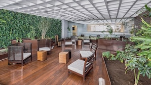 Uma área de lounge moderna com piso de madeira, assentos acolchoados e uma parede verde.