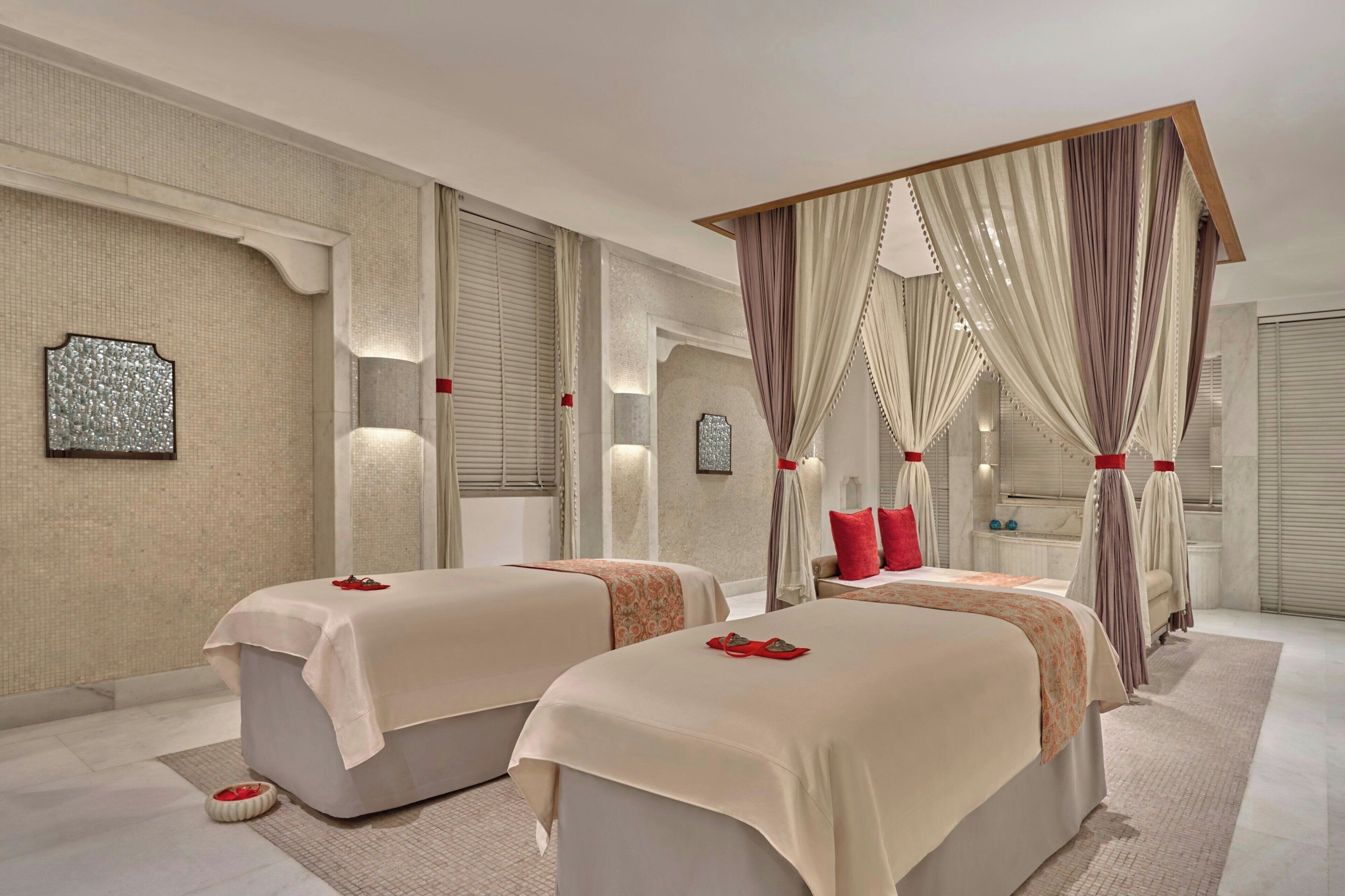 Quarto de hotel com duas camas, incluindo uma cama com dossel, e um espelho grande.