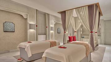 Quarto de hotel com duas camas, incluindo uma cama com dossel, e um espelho grande.