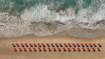 Na praia, espreguiçadeiras, guarda-sóis de praia, toalhas de praia