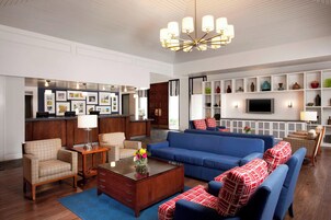 Uma sala de estar moderna com um sofá azul, mesa de centro de madeira e um candelabro.
