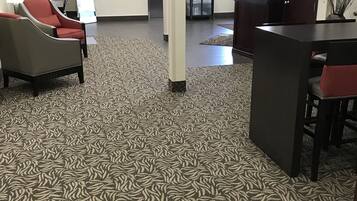 Um hall de hotel com carpete estampado, balcão de recepção e áreas de estar.