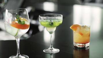 Três cocktails sobre uma superfície refletora.