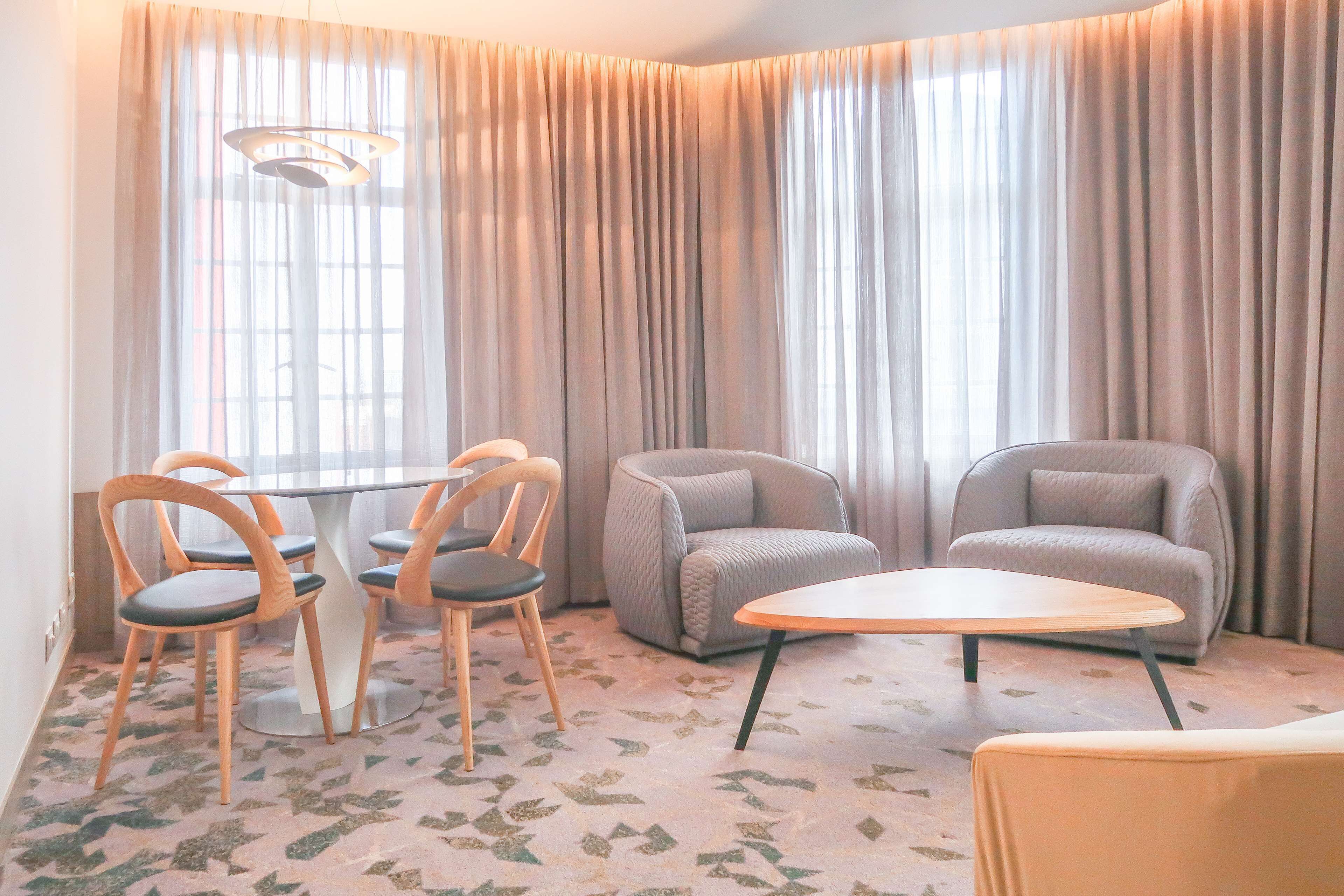 Um quarto com uma mesa de jantar, quatro cadeiras, dois sofás e um tapete estampado.