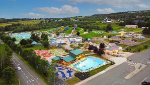 Vista aérea de um resort com piscina, toboáguas e um edifício grande com telhado verde.
