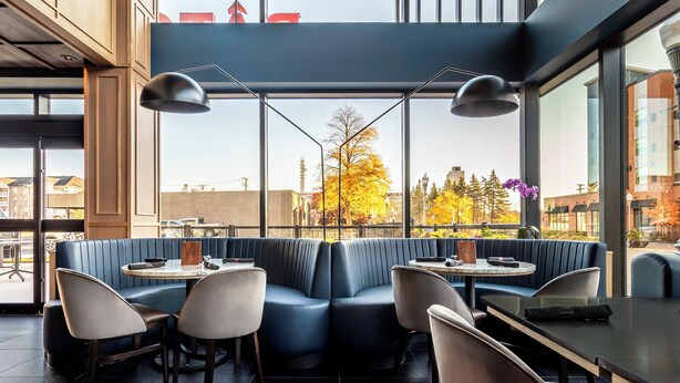 Um restaurante moderno com área de estar acolhedora, grandes janelas e vista para a cidade.