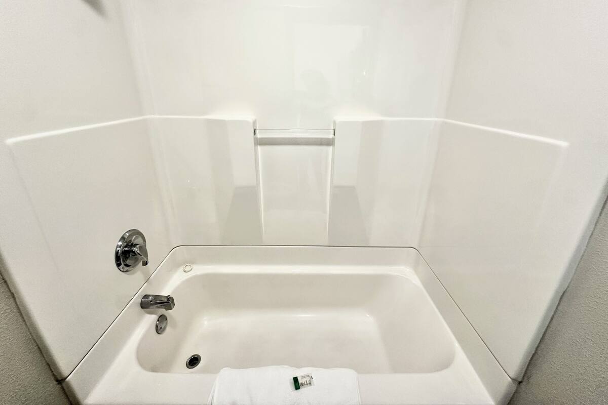 Uma banheira branca com uma torneira e um porta-toalhas.