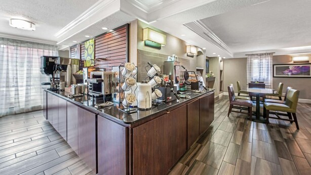 Um lobby de hotel moderno com um balcão central, área de estar e uma mesa de jantar.