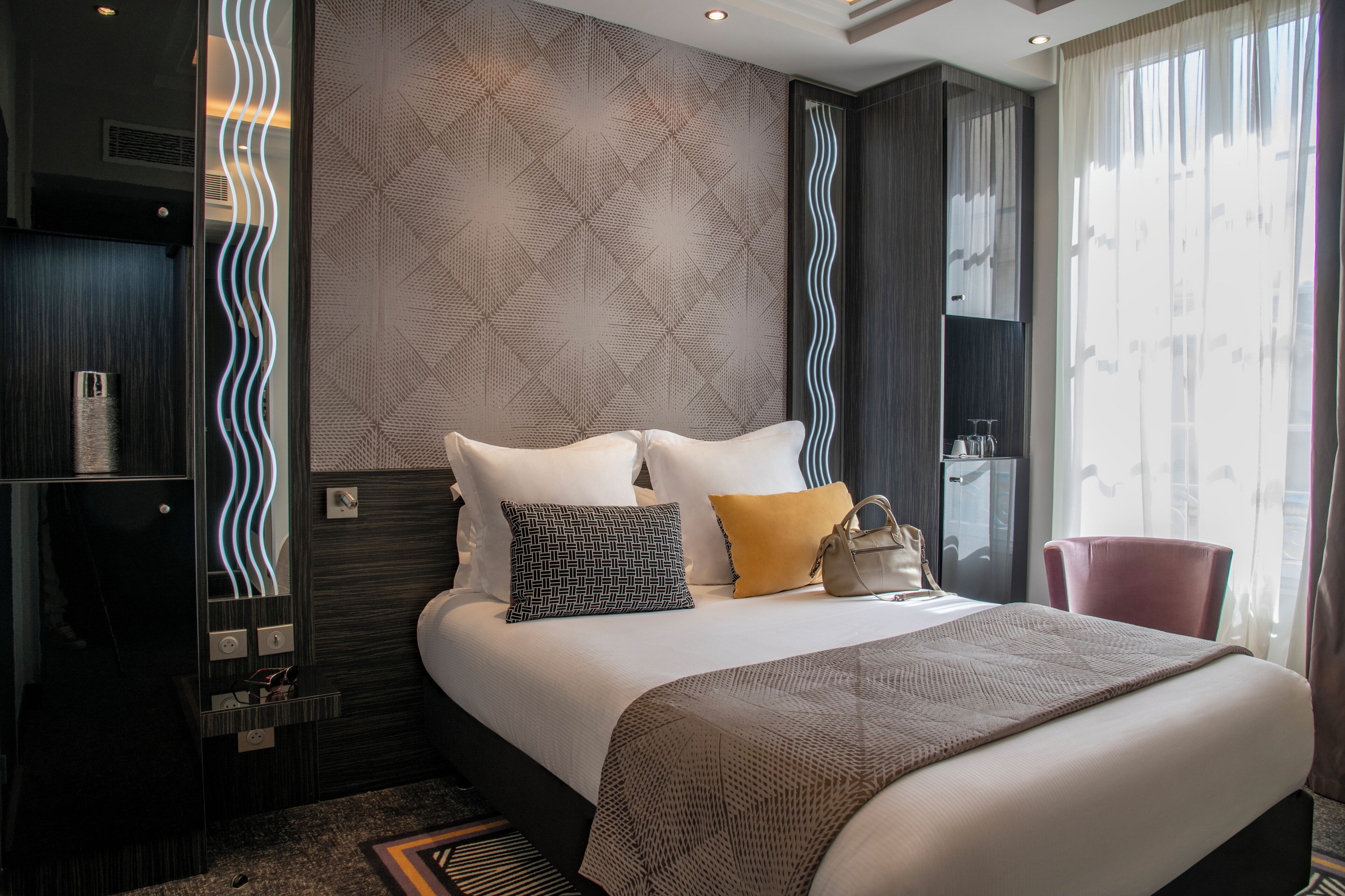 Quarto de hotel moderno com uma cama grande, um guarda-roupa e uma cômoda com espelho.