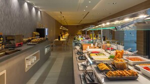 Buffet variado com diversos alimentos e estação de bebidas de serviço por autoatendimento.