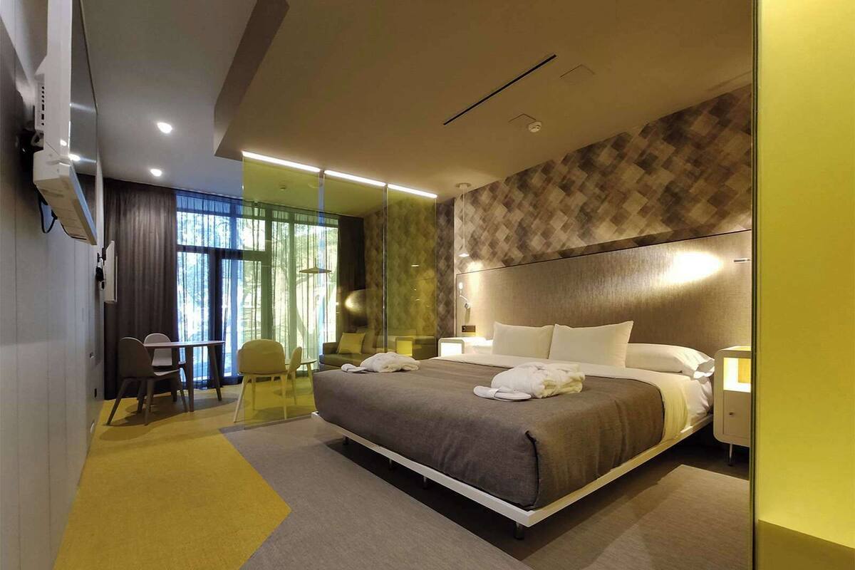Quarto de hotel moderno com uma cama grande, uma escrivaninha e uma cadeira.