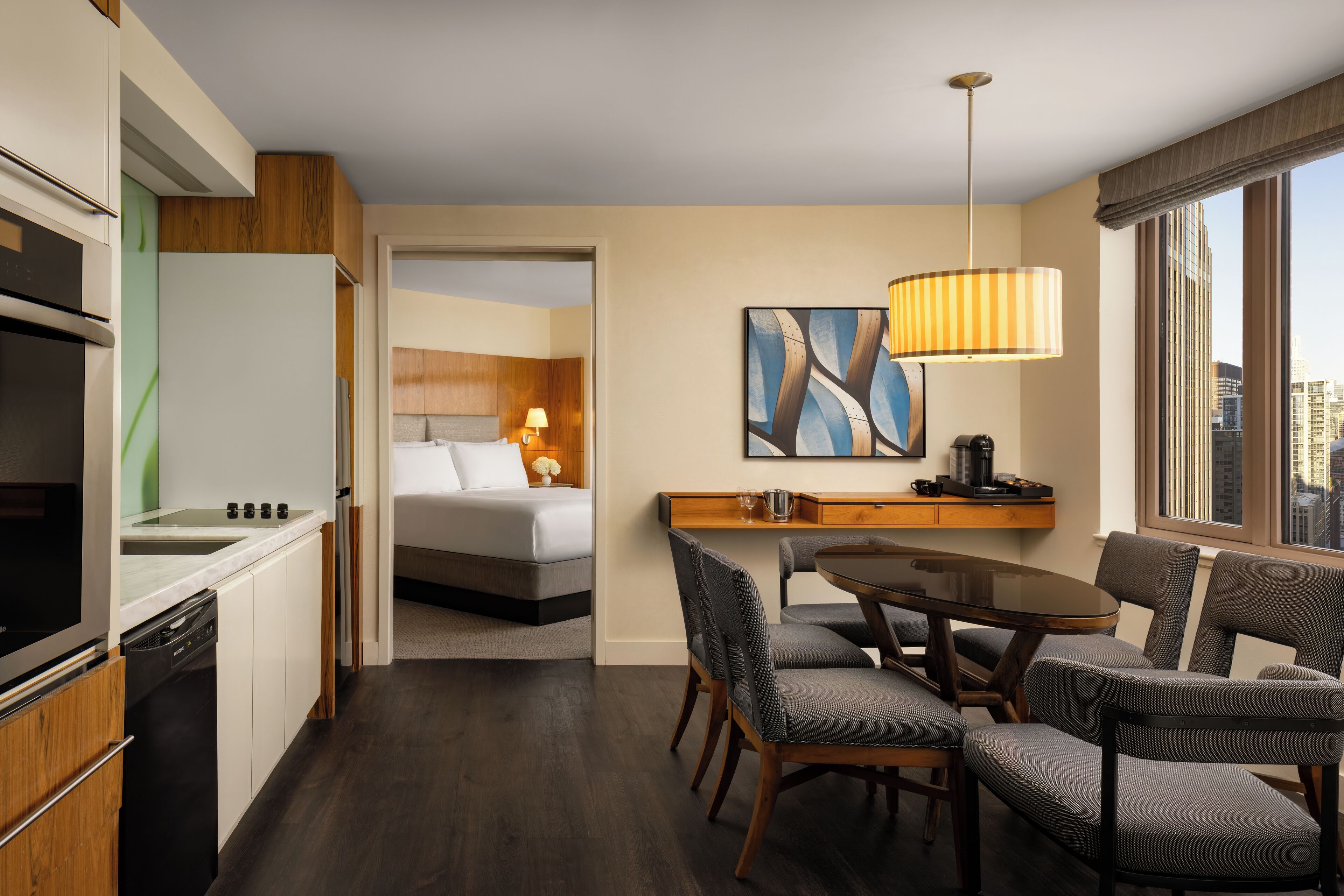 Quarto de hotel moderno com cozinha, sala de jantar e uma cama.