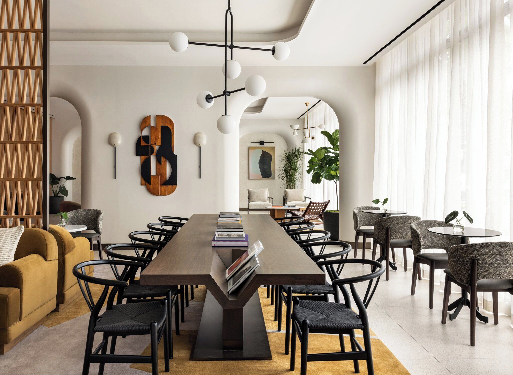 Uma área de jantar moderna com uma mesa comprida, várias cadeiras e uma obra de arte central.