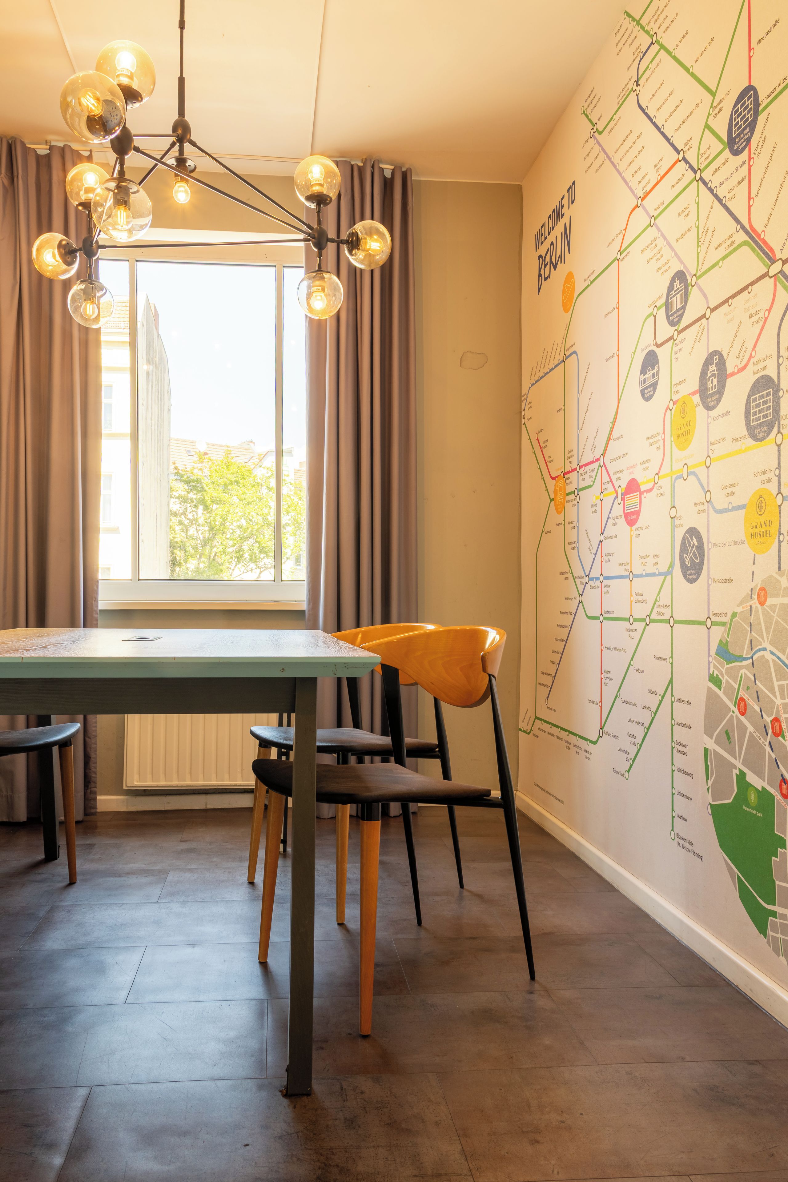 Quarto com mesa de jantar, cadeiras, mapa na parede e janela com cortinas.
