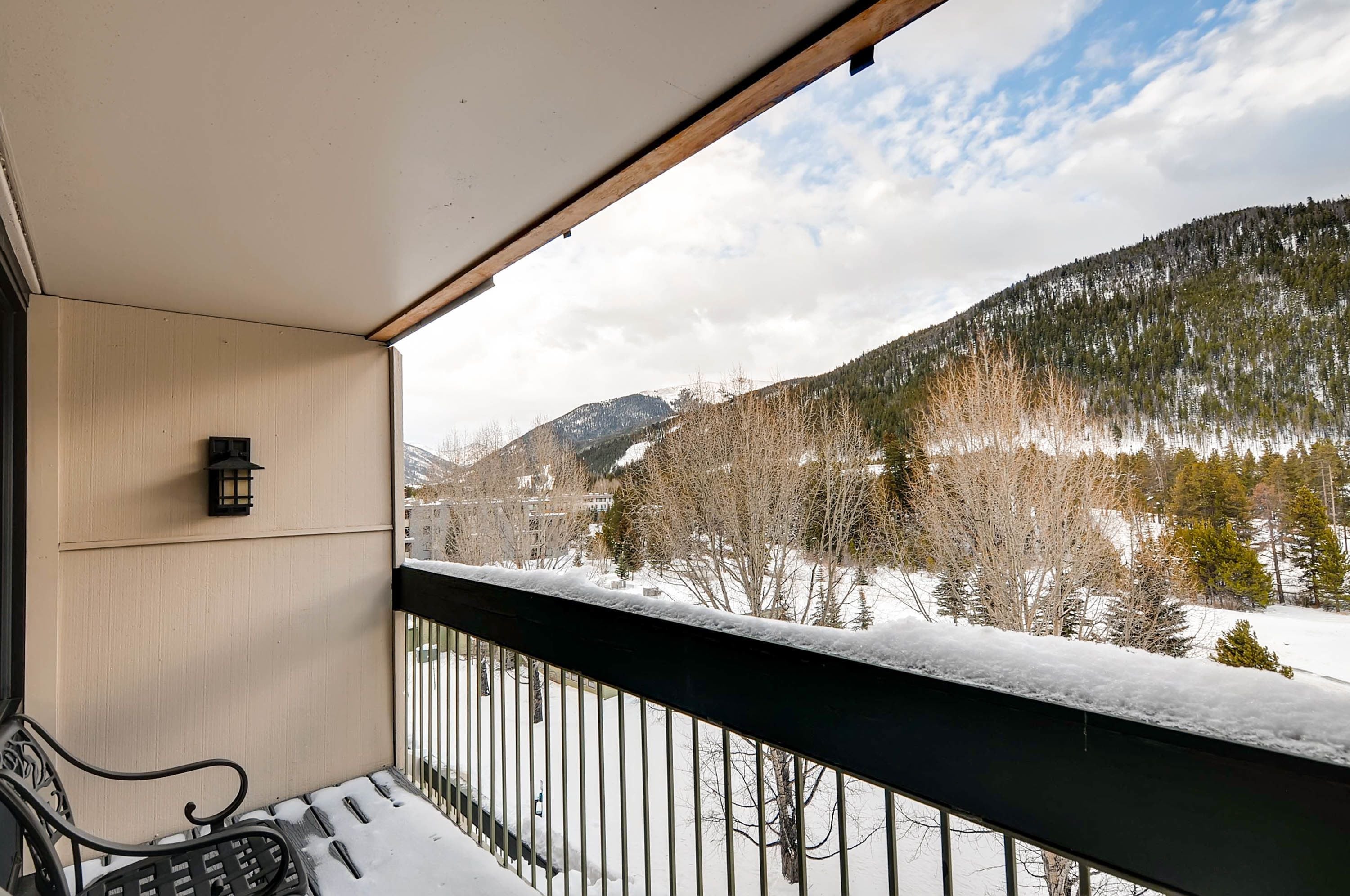 Uma varanda com vista para árvores e montanhas cobertas de neve.