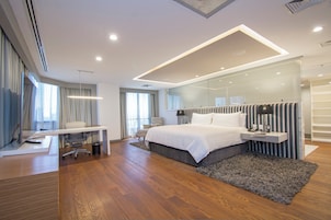 Quarto moderno com uma cama grande, mesas de cabeceira, uma escrivaninha e uma cadeira.