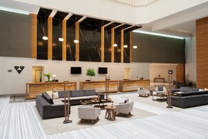 Um hall amplo com design moderno, com uma mesa de recepção, sofás e uma grande área de estar.