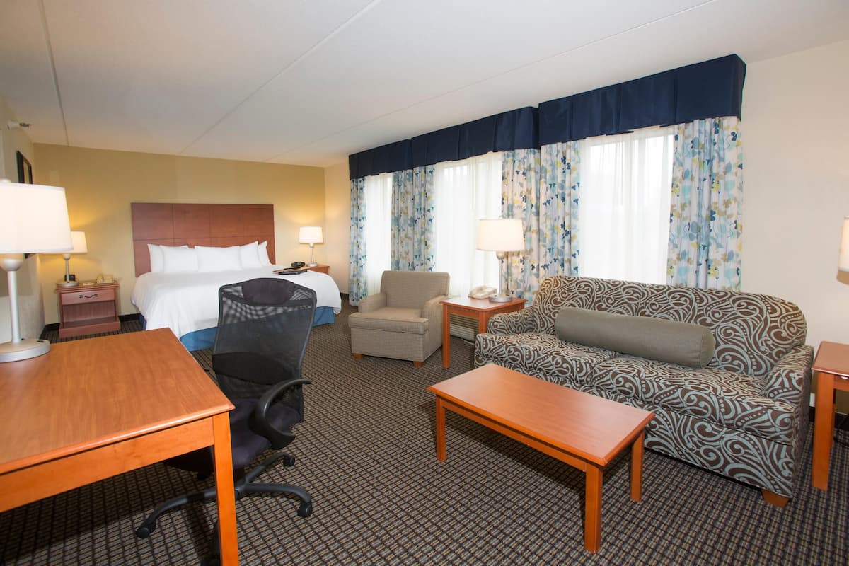 Quarto de hotel com cama, sofá, escrivaninha, cadeira e mesa.