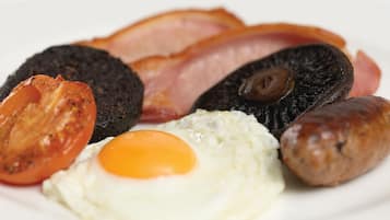 Prato de comida de café da manhã com ovos, salsichas, bacon e tomates.