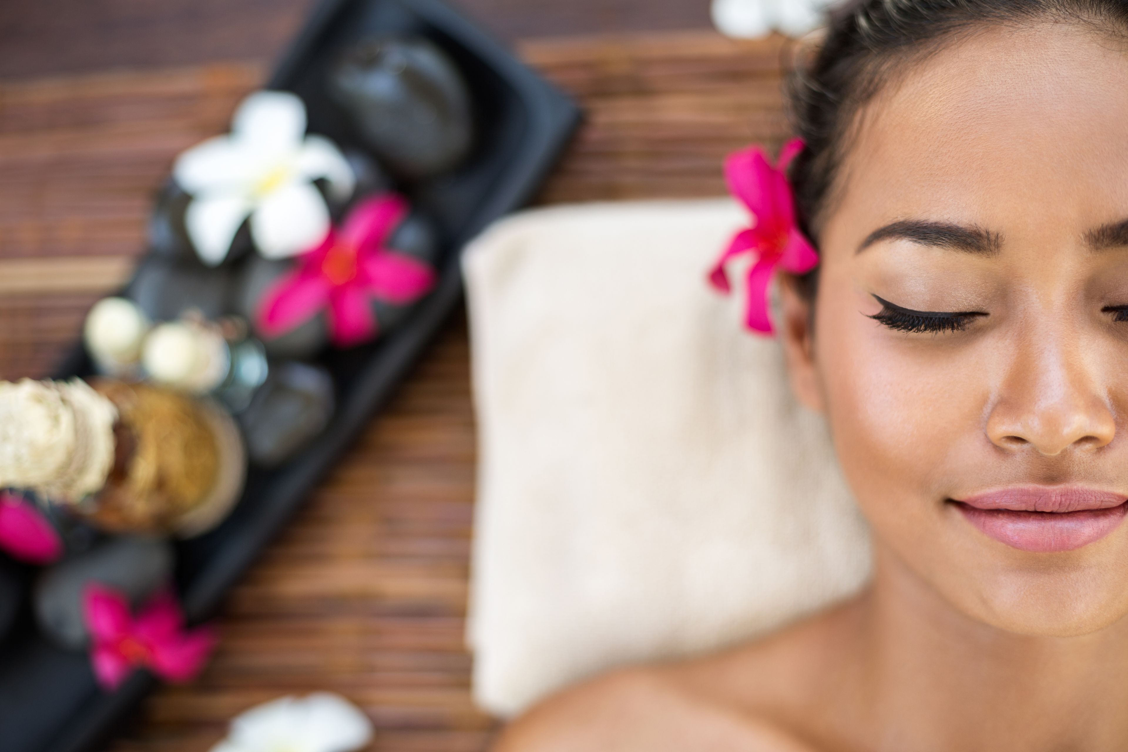 Um espaço de spa com mesa de massagem, bandeja de sais de banho e flores.