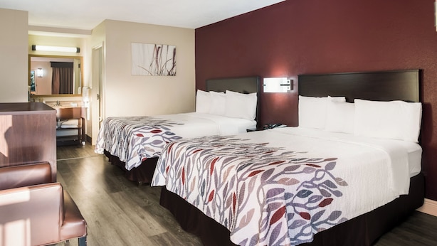 Quarto de hotel com duas camas, uma escrivaninha e um espelho.