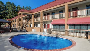 Um hotel com piscina, área de estar externa e um edifício com telhado vermelho.
