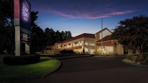 Hotel com grande placa indicando serviços para animais de estimação, área de estacionamento coberta e gramado bem cuidado.