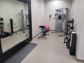 Ginásio com equipamentos de exercício, espelho e bola de ginástica vermelha.
