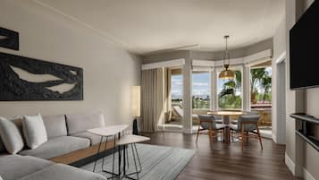 Uma sala de estar moderna com sofá, mesa de centro, área de jantar e janelas amplas.