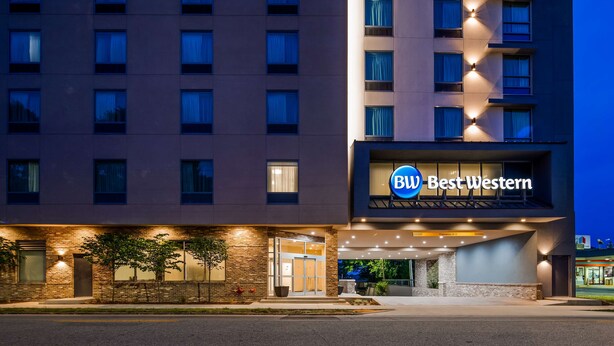Um hotel com fachada moderna, um destaque para a placa 'BW Best Western' e uma entrada bem iluminada.