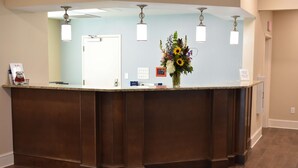 Bancada de recepção com um vaso de flores, guarda-volumes e um aviso com os horários de check-in.