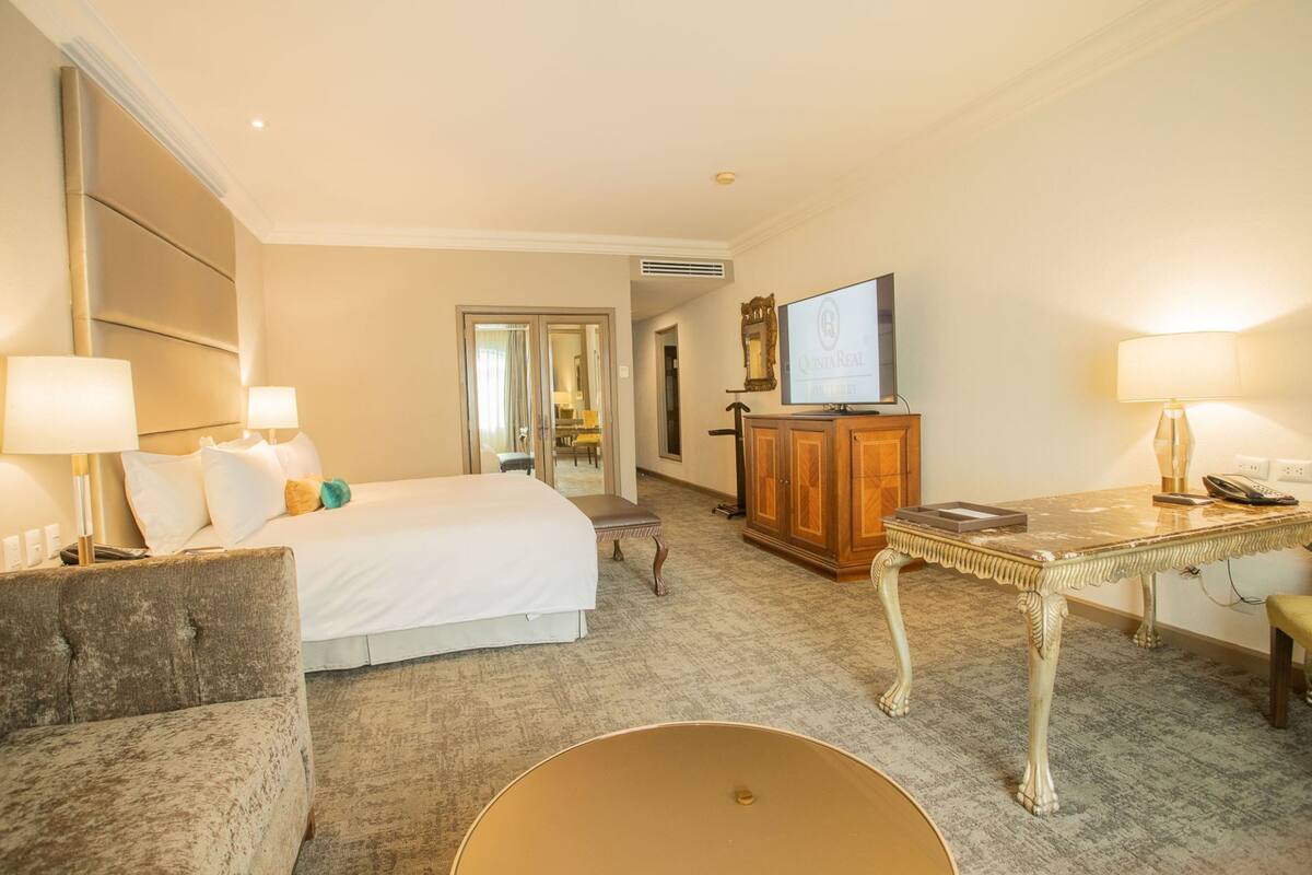 Quarto de hotel com uma cama grande, uma escrivaninha, uma televisão e um armário.