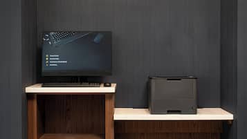 Um espaço de trabalho moderno com monitor de tela plana, teclado e impressora sobre uma mesa de madeira em frente a uma parede texturizada.