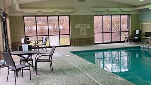 Uma piscina interior com azulejos, um aviso de salva-vidas e espreguiçadeiras.