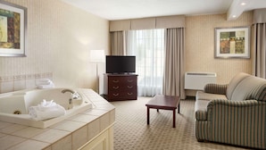 Quarto de hotel com banheira, televisão, sofá e uma mesinha.