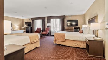 Quarto de hotel com duas camas, uma escrivaninha, uma cadeira, uma televisão e uma janela com cortinas.