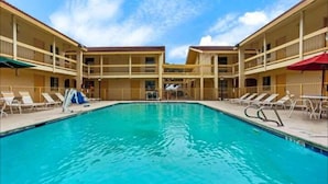 Um hotel com piscina central, várias varandas e espreguiçadeiras.