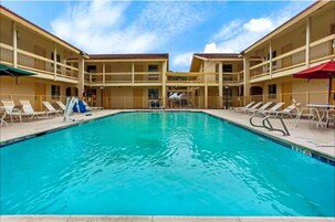 Um hotel com piscina central, várias varandas e espreguiçadeiras.