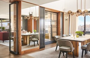 Uma sala de jantar moderna com uma mesa grande, cadeiras e um candelabro.
