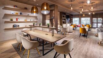 Uma sala de jantar moderna com mesa de madeira, cadeiras bege e iluminação pendente.