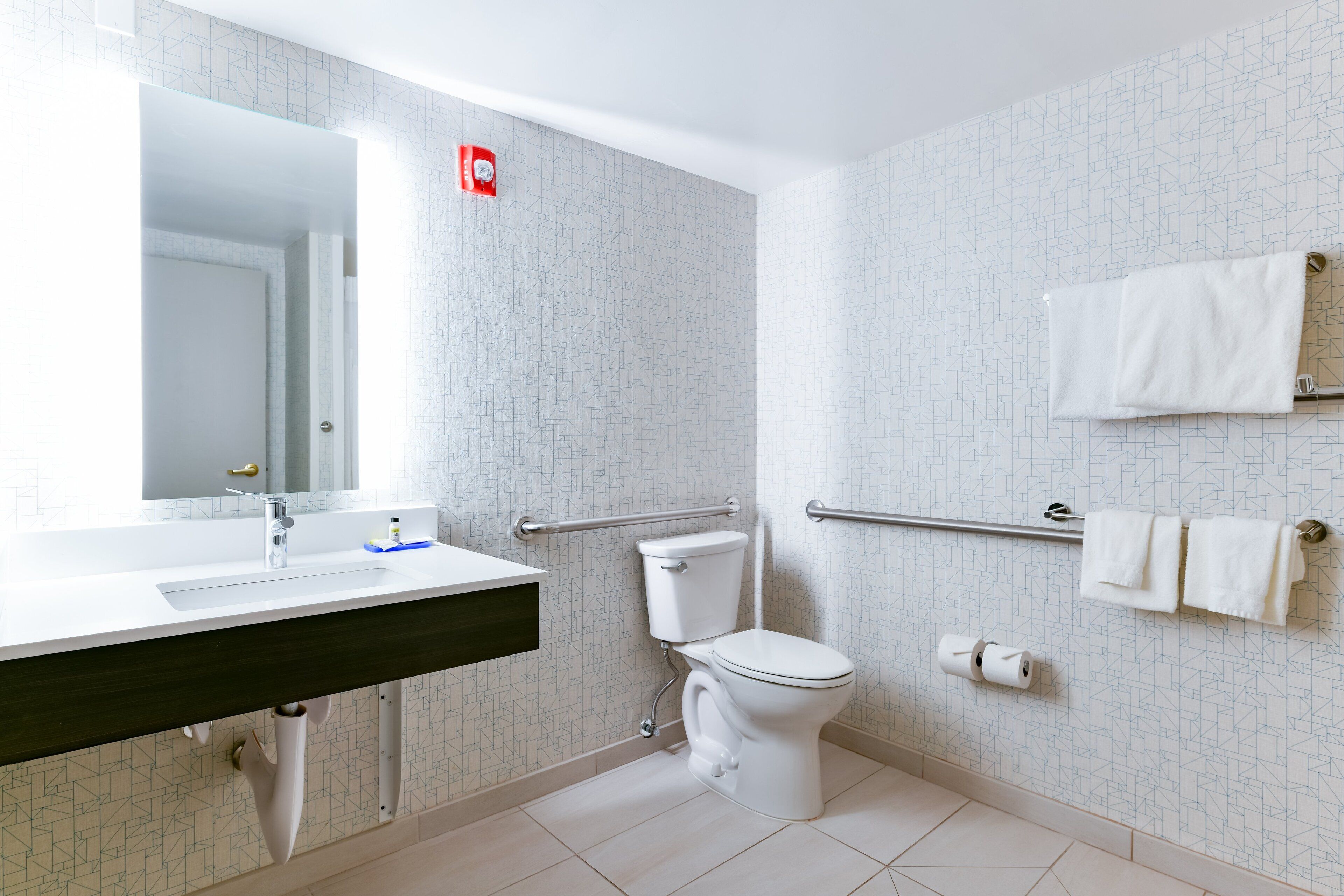 Casa de banho moderna com lavatório branco, sanita e porta-toalhas.