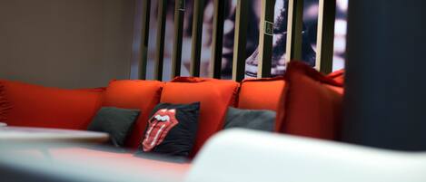 Um interior moderno com um conjunto de sofá com almofadas vermelhas e um travesseiro preto com detalhe em vermelho.