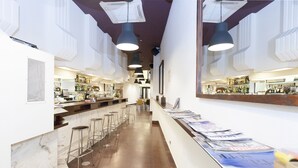 Uma área de bar moderna com um balcão comprido, banquetas e iluminação pendente.