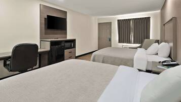 Quarto de hotel com duas camas, uma escrivaninha com televisão, micro-ondas e telefone.